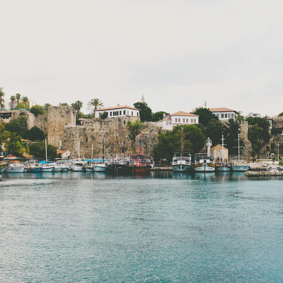 Antalya harbor at sunset with boats and historic buildings in golden light