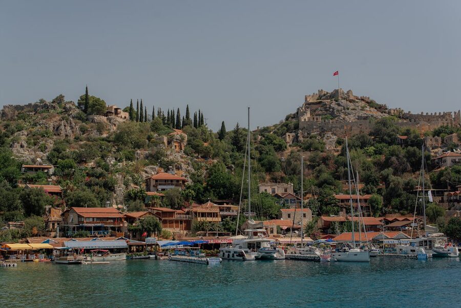 Boats in Kekova harbor with Kalekoy village and castle on the hillside