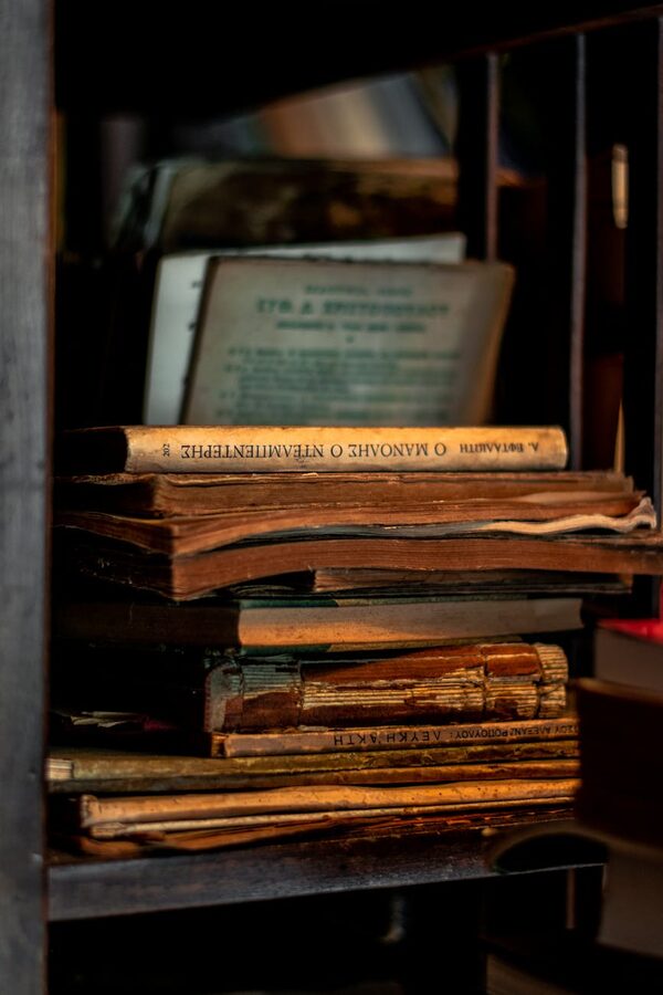 Stack of antique books and manuscripts on a dark wooden shelf