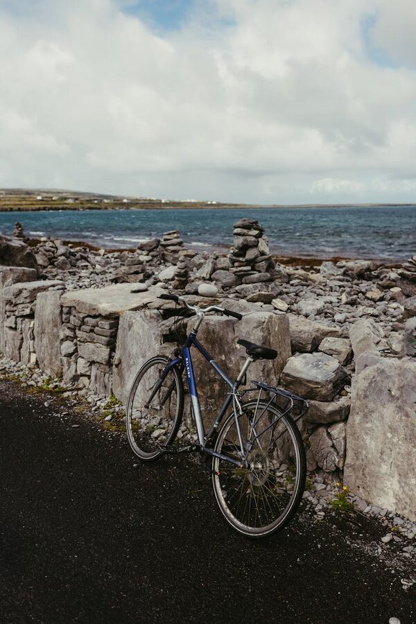 Bicycle leaning against a stone wall on Inishmore with rocky coastline