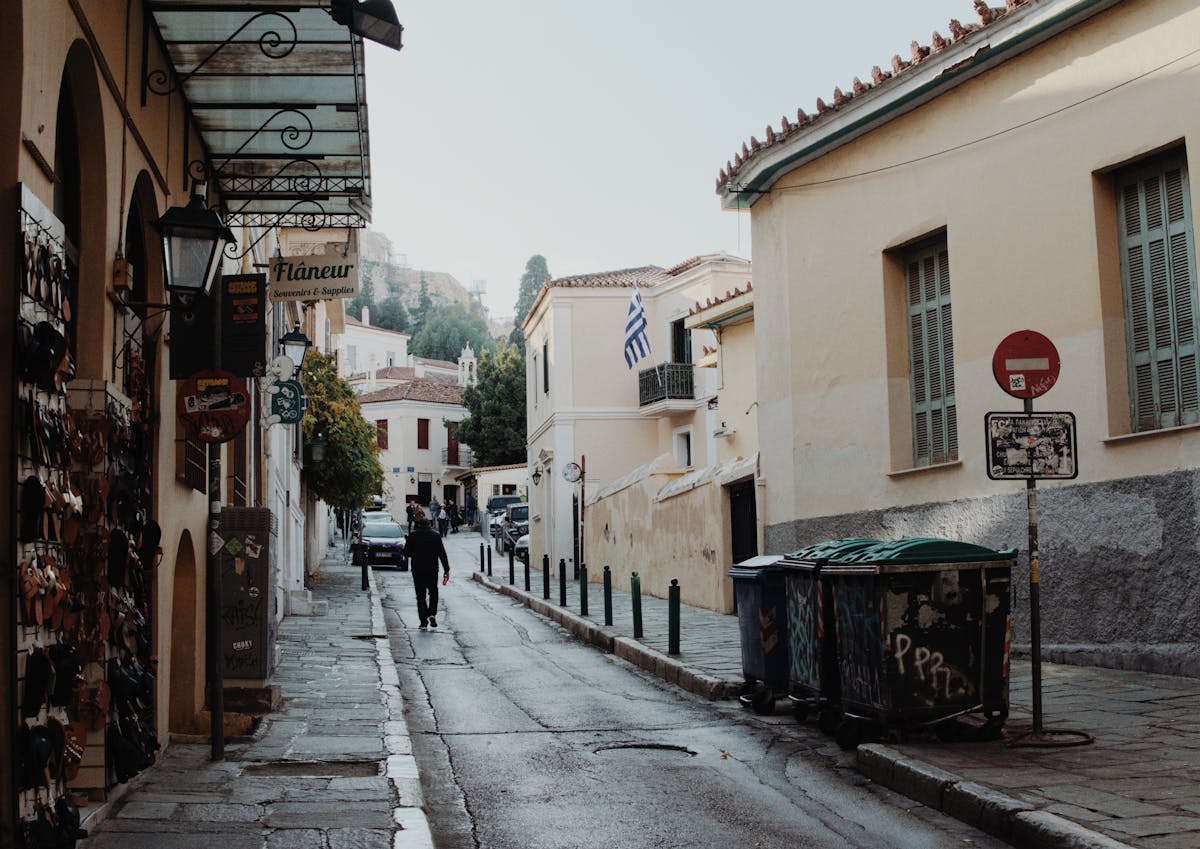 Quiet street in Athens historic Plaka district with shops and Greek flag