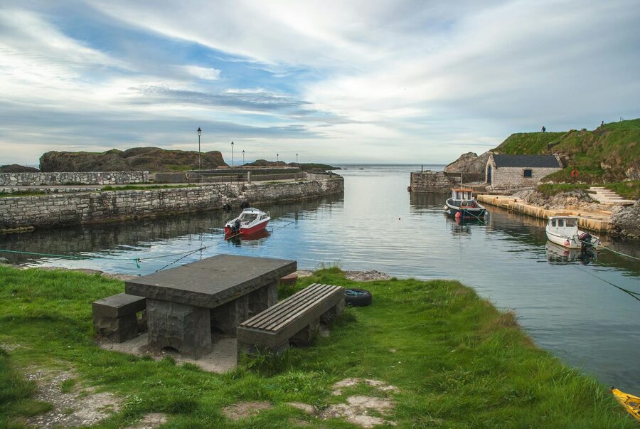 Ballintoy Harbour with boats and cloudy sky in Northern Ireland