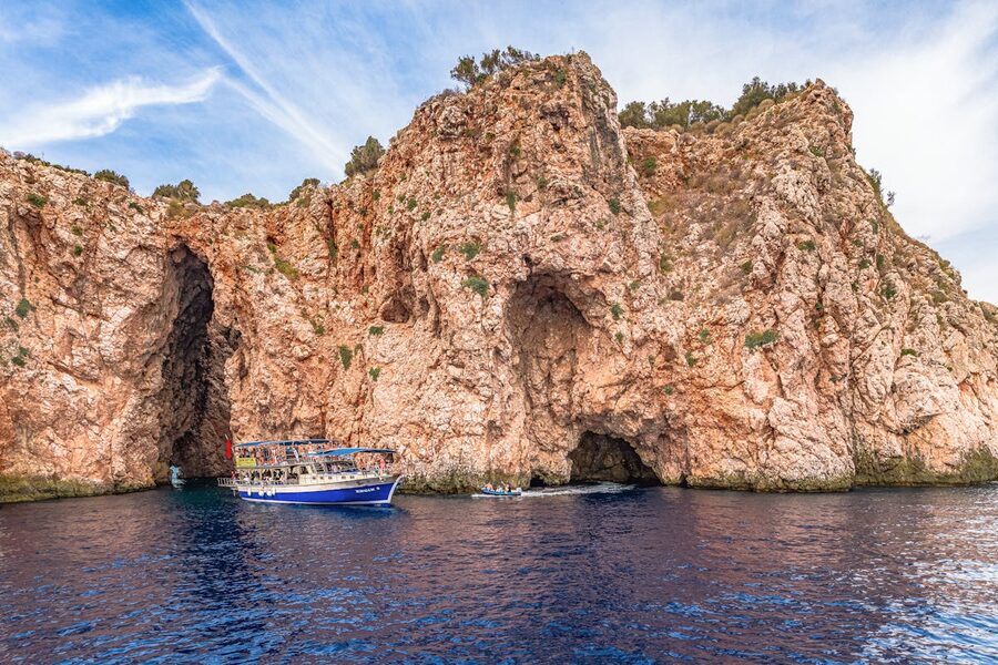 Boat by rugged cliffs and sea caves in coastal setting