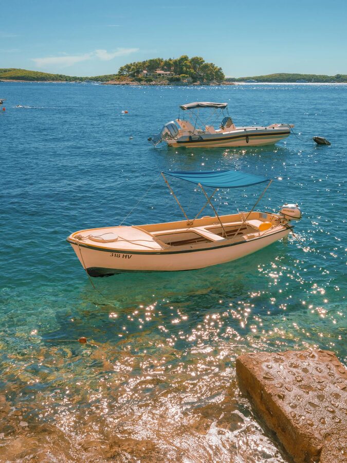 Boats on clear blue sea with islands in background
