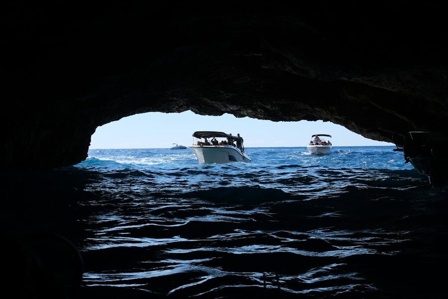 Boats inside a dark sea cave with light through water