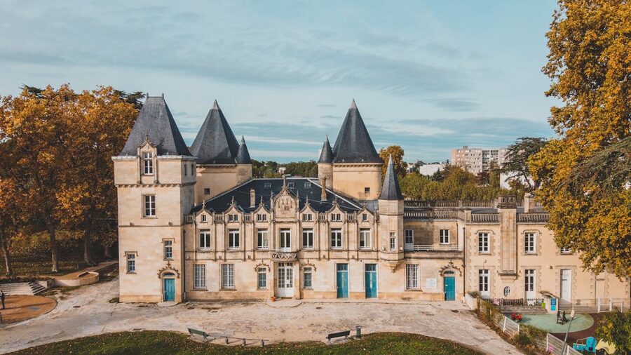 Aerial view of a Bordeaux chateau surrounded by autumn vineyards