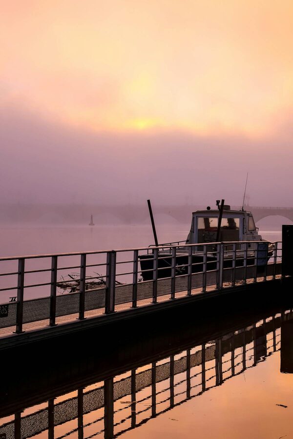 Tranquil sunrise over the Garonne River in Bordeaux with boats and hazy sky