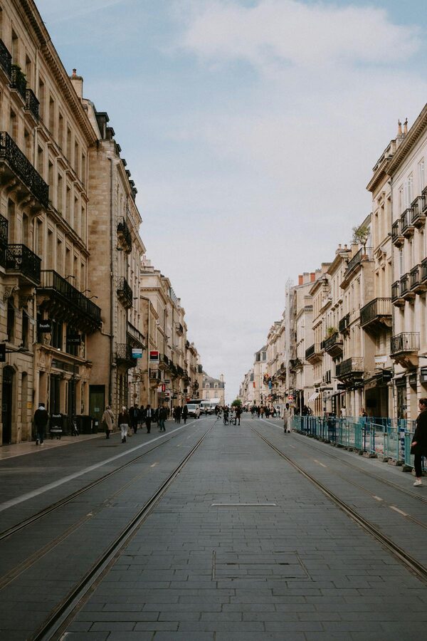 Wide Bordeaux street lined with historic residential buildings and a clear blue sky