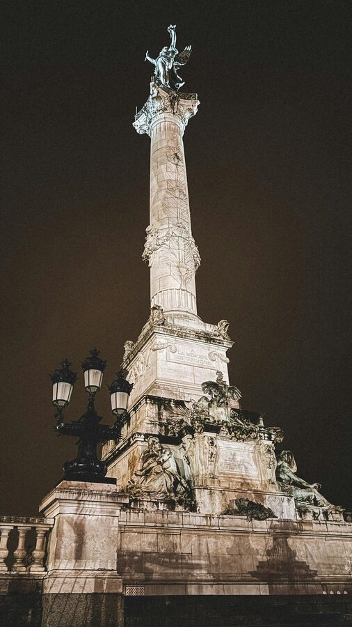 Monument aux Girondins in Bordeaux illuminated at night with light trails from passing traffic