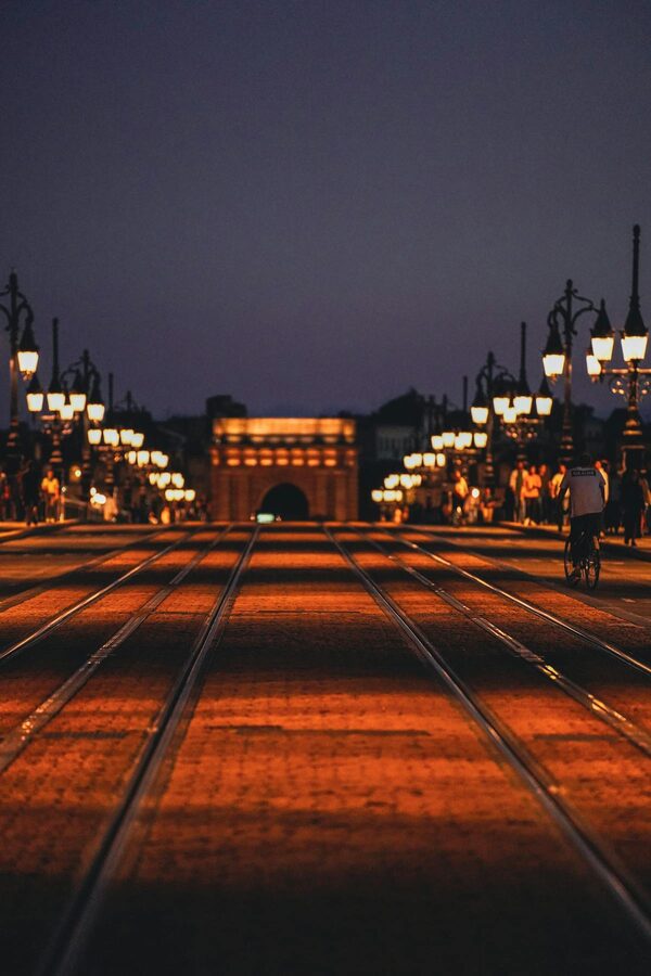 Illuminated Bordeaux street at night with tram tracks and warm lighting