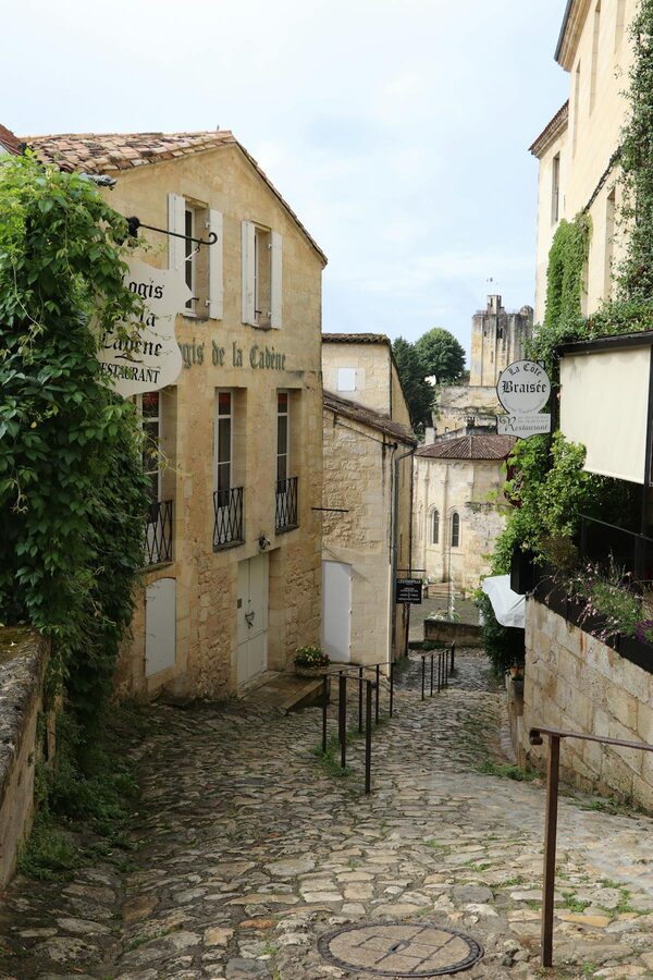 Cobblestone lane in Saint-Émilion lined with stone buildings and wine shop signs