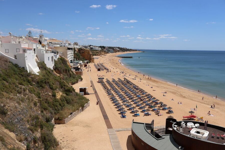 Albufeira beach with cliffs umbrellas and clear blue skies Algarve