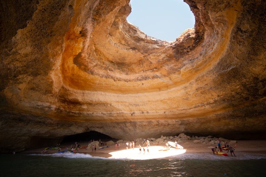 People under the skylight inside Benagil sea cave with sunlight shaft