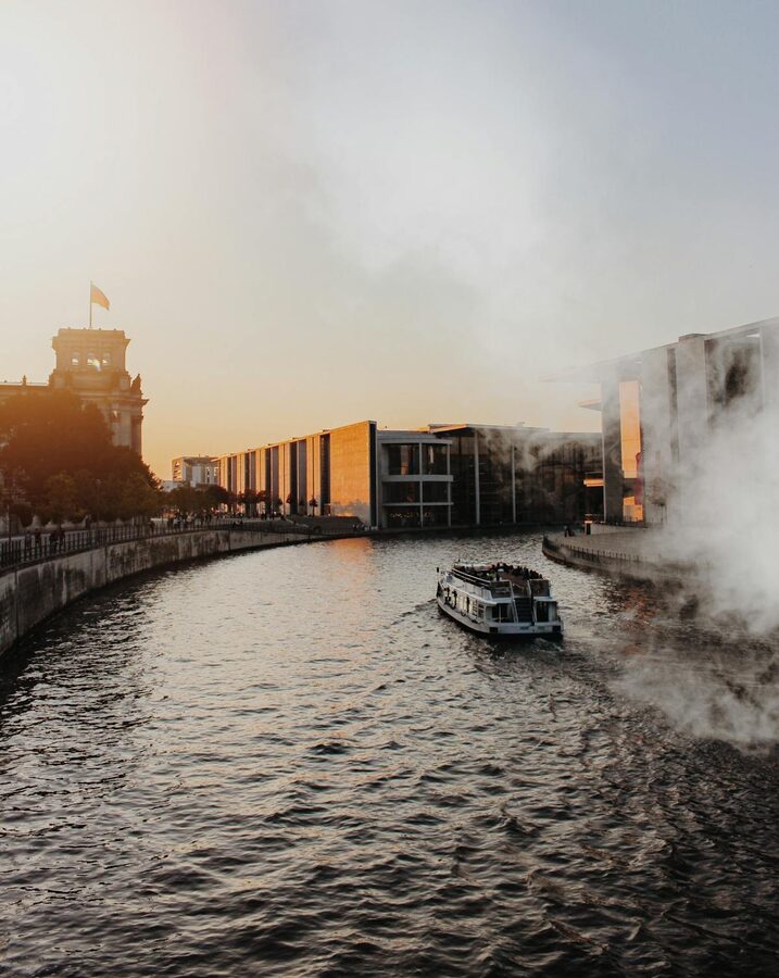 Aerial view of a ferry boat navigating the Spree River past government buildings in Berlin at sunset