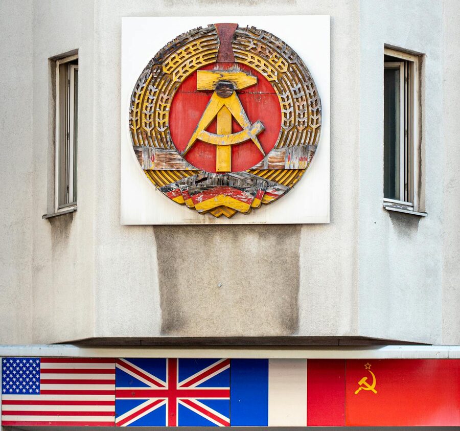 East German emblem and international flags at a Berlin Cold War landmark