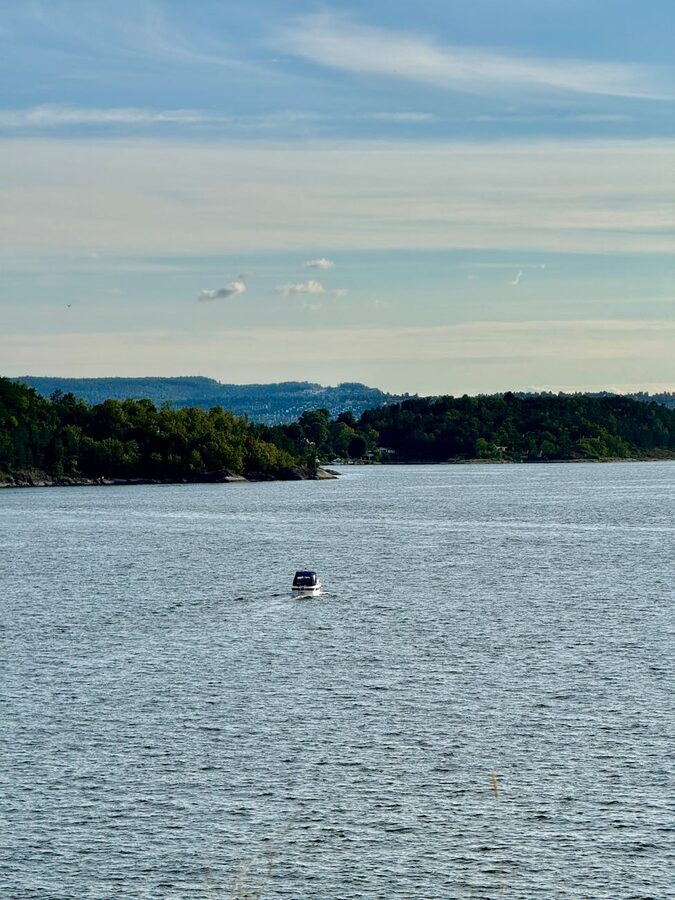 Boat sailing on Oslo fjord surrounded by green islands under summer sky