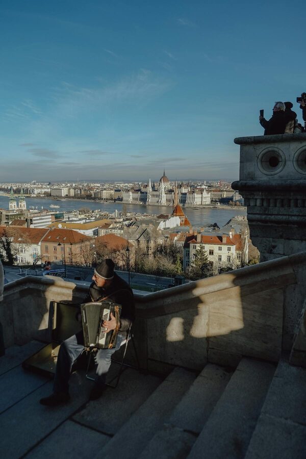 Street musician playing accordion with Budapest cityscape