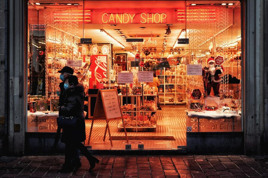 Couple walking past illuminated candy shop in Bruges