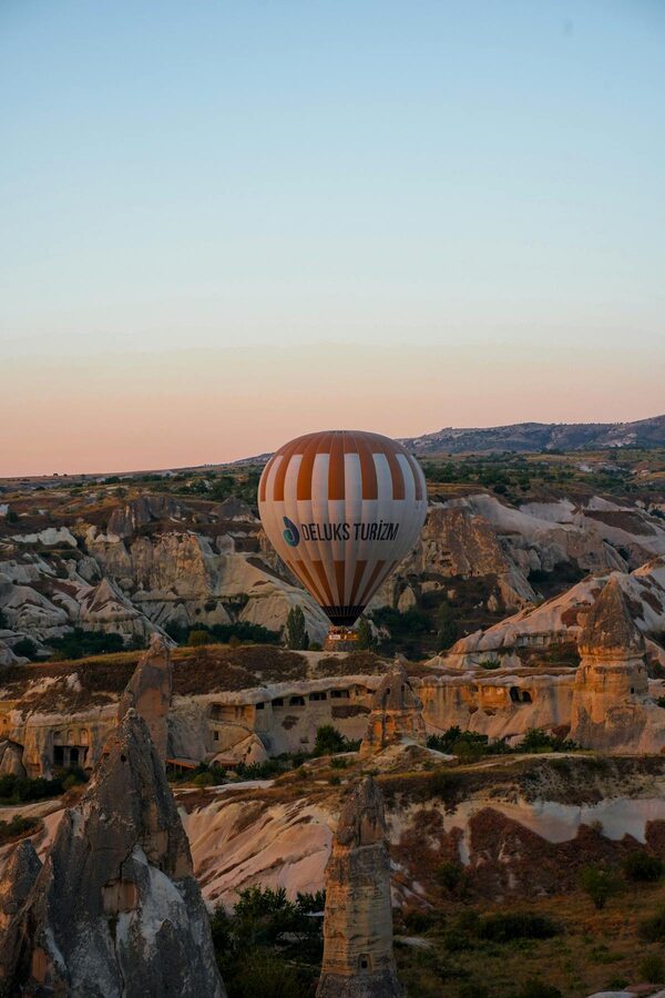 Hot air balloon floating over rock formations of Cappadocia at sunrise