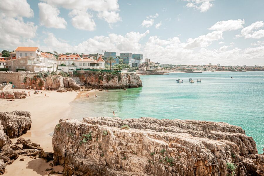 Sandy beach and turquoise water along coastal cliffs in Cascais Portugal
