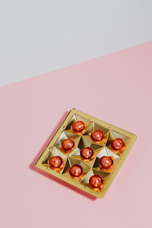Wrapped chocolate pralines on pink surface