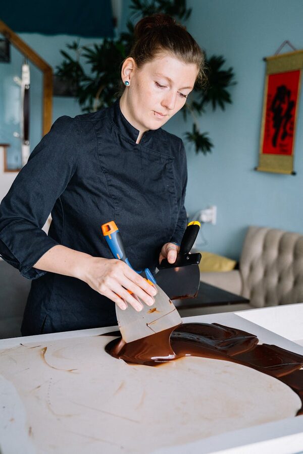 Woman tempering chocolate on marble table