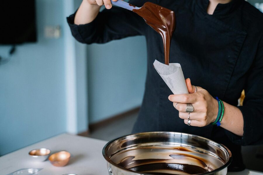 Chef pouring melted chocolate into piping bag