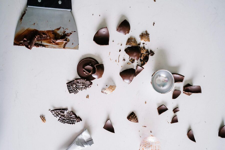 Flatlay of chocolate pieces and scraper on white surface