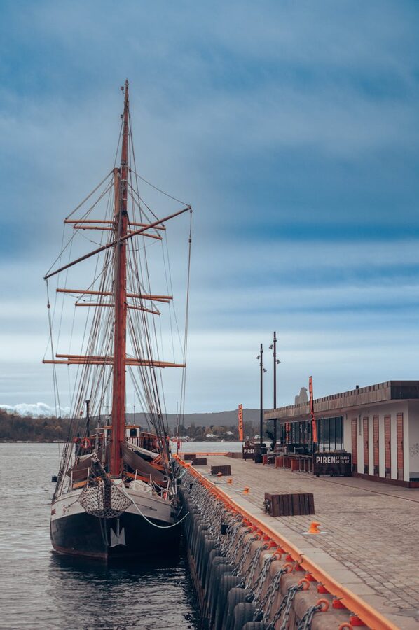 Classic ship docked at Oslo waterfront against vivid sky