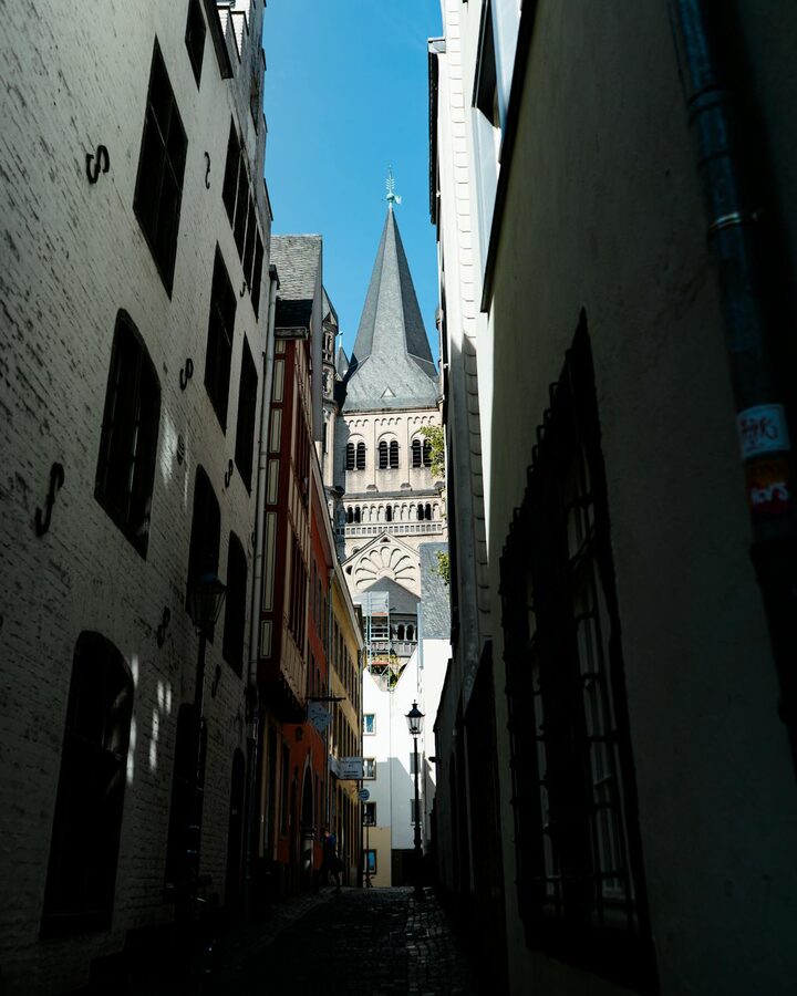 Gothic architecture tower viewed through narrow alleyway in Cologne Germany