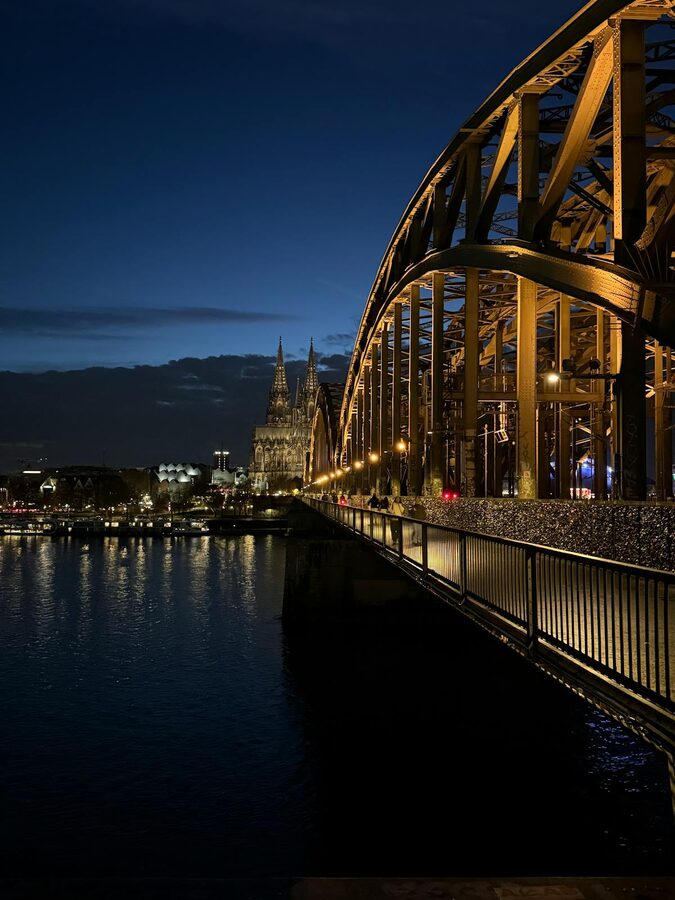 Twilight view of Hohenzollern Bridge and Cologne Cathedral reflected in Rhine