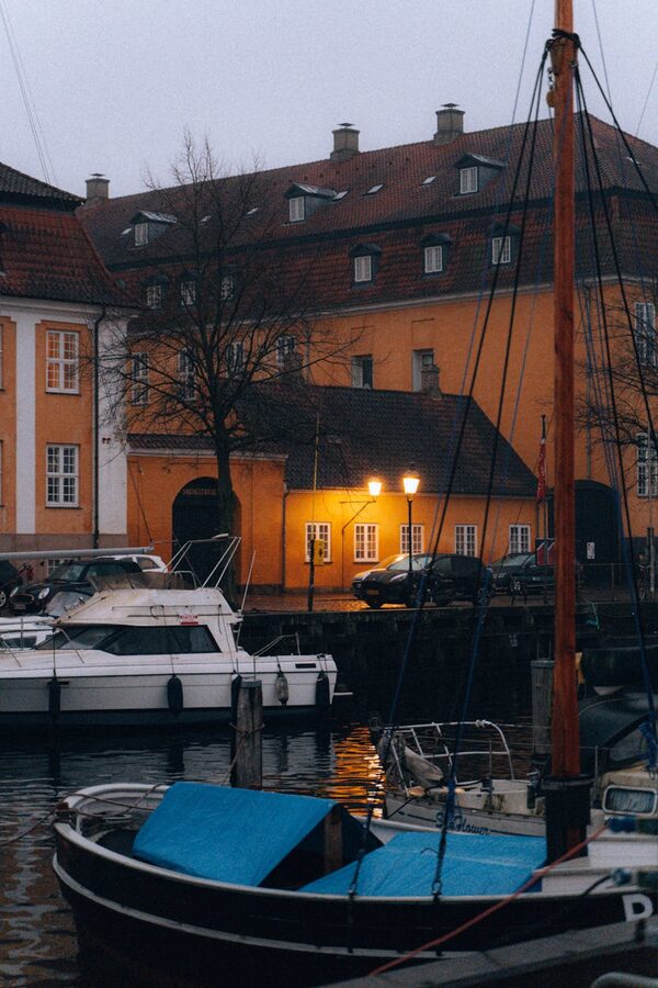 Copenhagen marina at twilight with boats and warm lights reflected in water