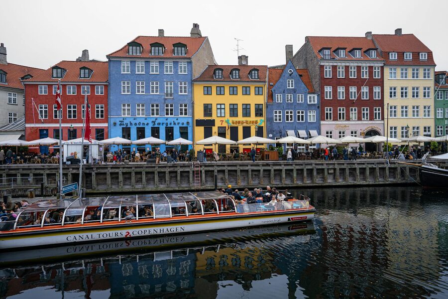 Canal tour boat passing through Nyhavn with colorful buildings behind