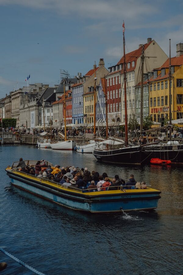 Canal tour boat moving through Copenhagen waters with colourful buildings