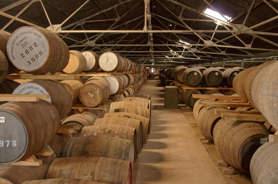 Rows of oak barrels ageing whiskey in a distillery warehouse