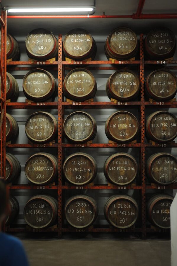 Whiskey barrels stacked vertically in a distillery storage room