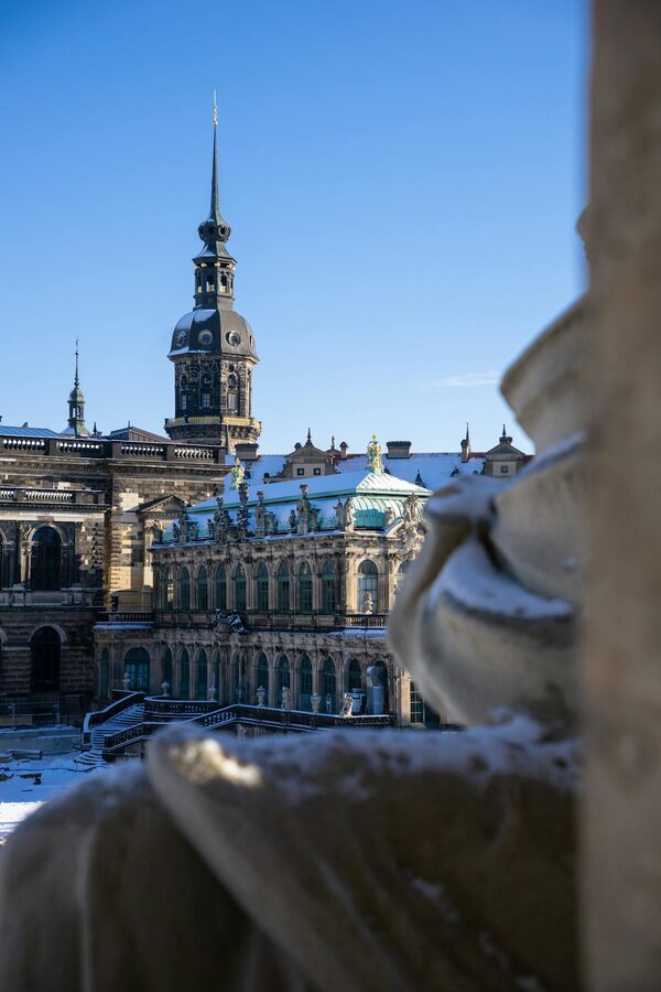 Zwinger Palace in snow with Dresden Clock Tower under clear winter sky