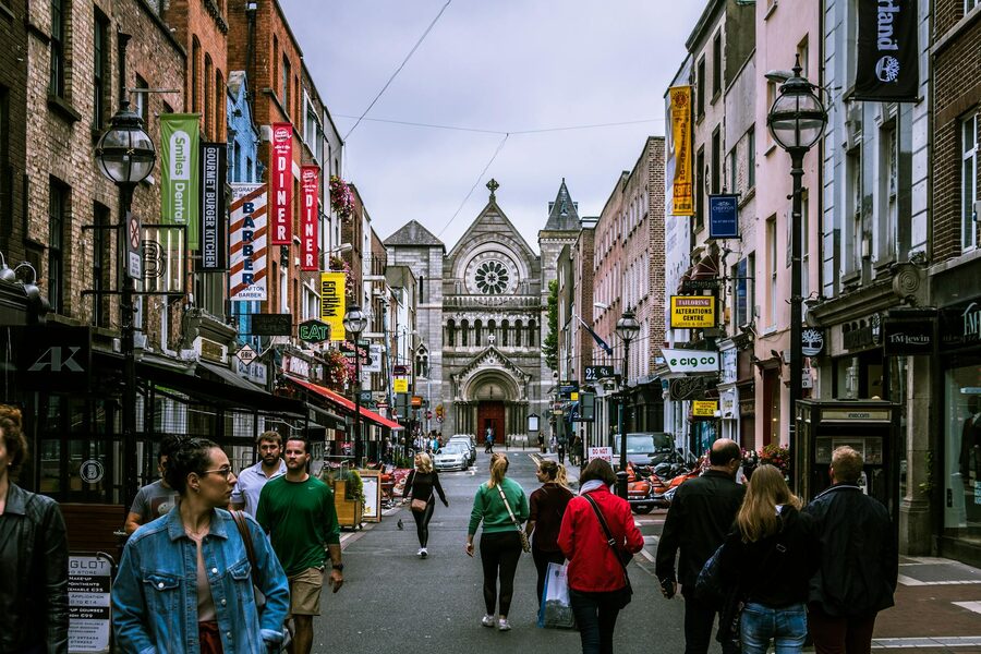 Pedestrians walking past historic buildings on a Dublin street