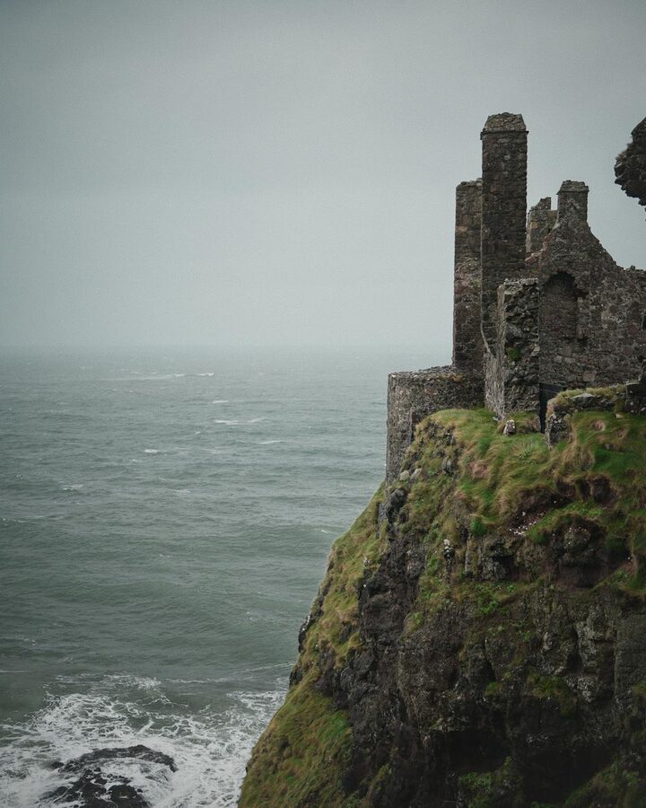 Moody view of Dunluce Castle on rugged cliffs above the North Atlantic
