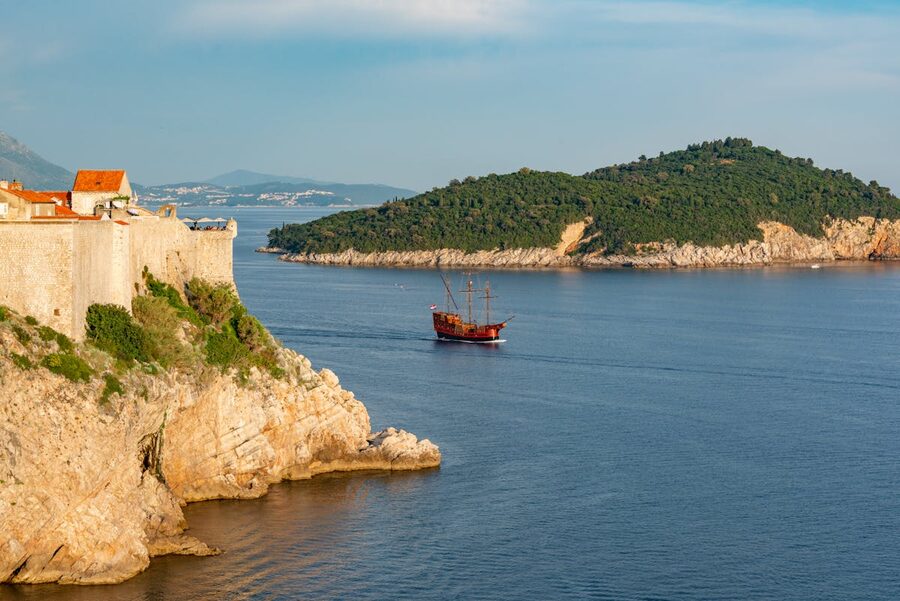 Dubrovnik coastline with old ship sailing near rocky cliff