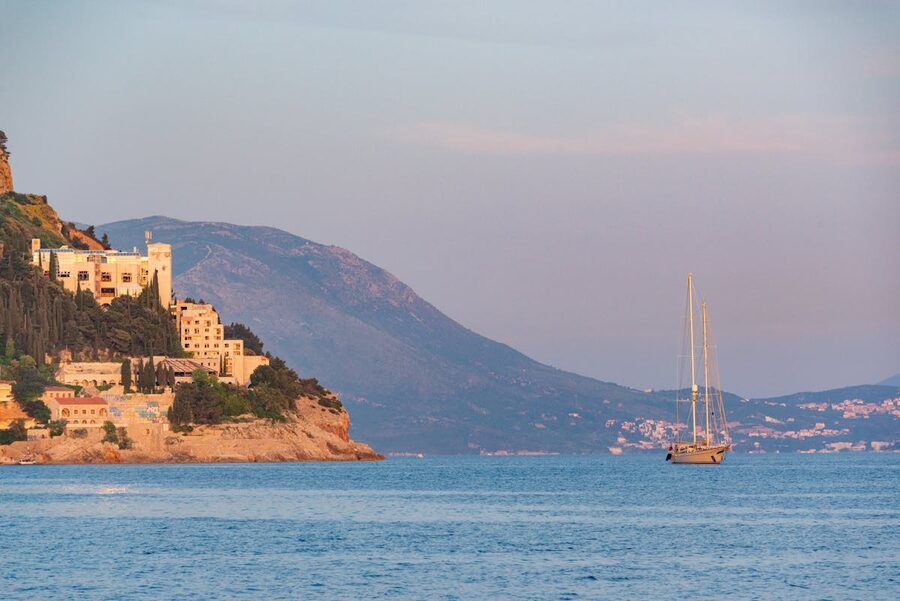 Sunset view of Dubrovnik coast with sailboat on Adriatic Sea