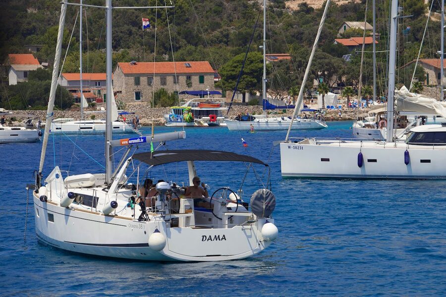 Sailing yachts in Mediterranean bay with houses and greenery