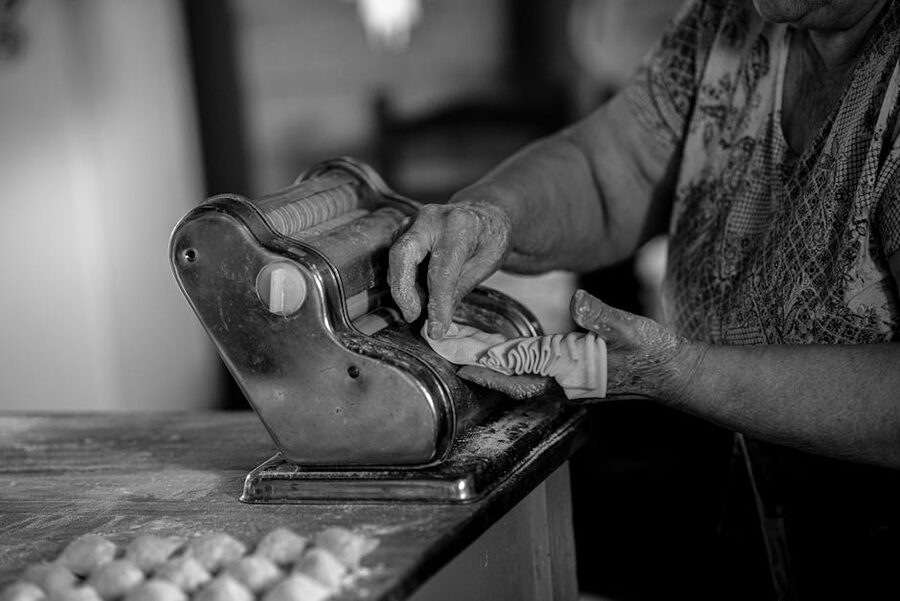 Elderly Italian woman using pasta machine
