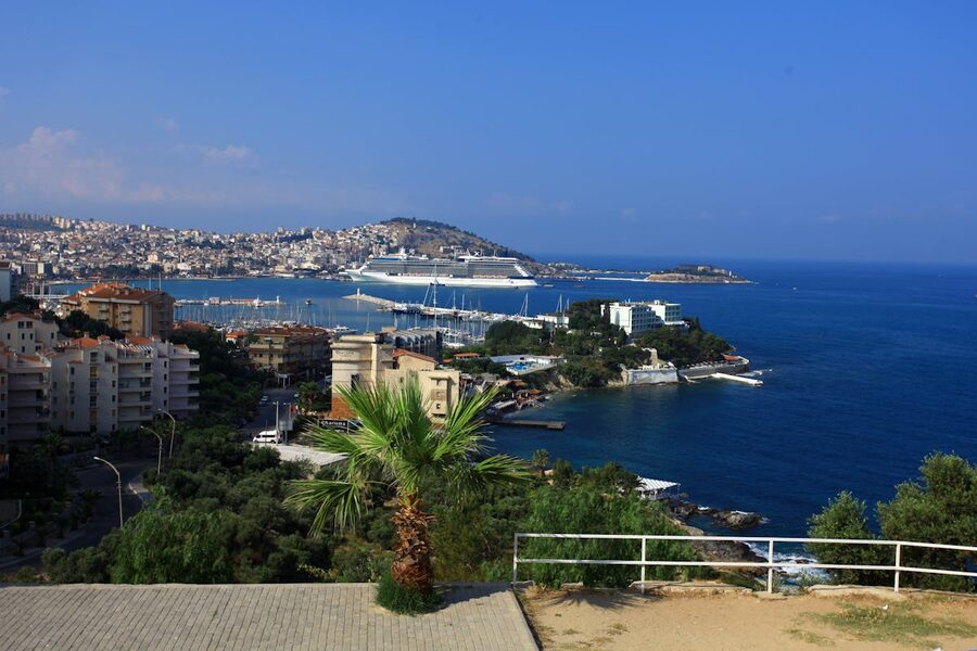 Coastal view of Kusadasi with cruise ship in the harbor under blue sky