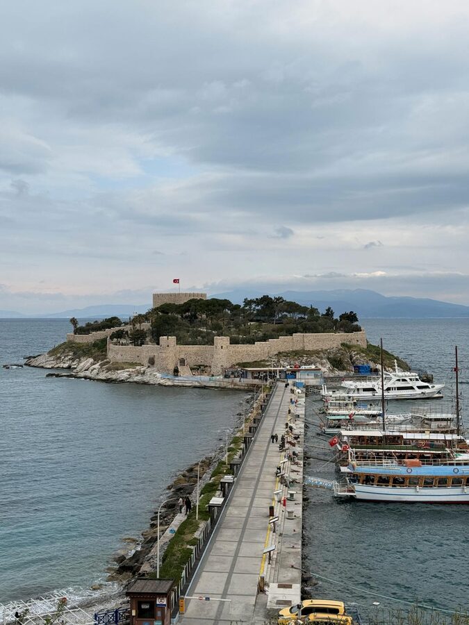 Kusadasi fortress and harbor with boats moored along the waterfront