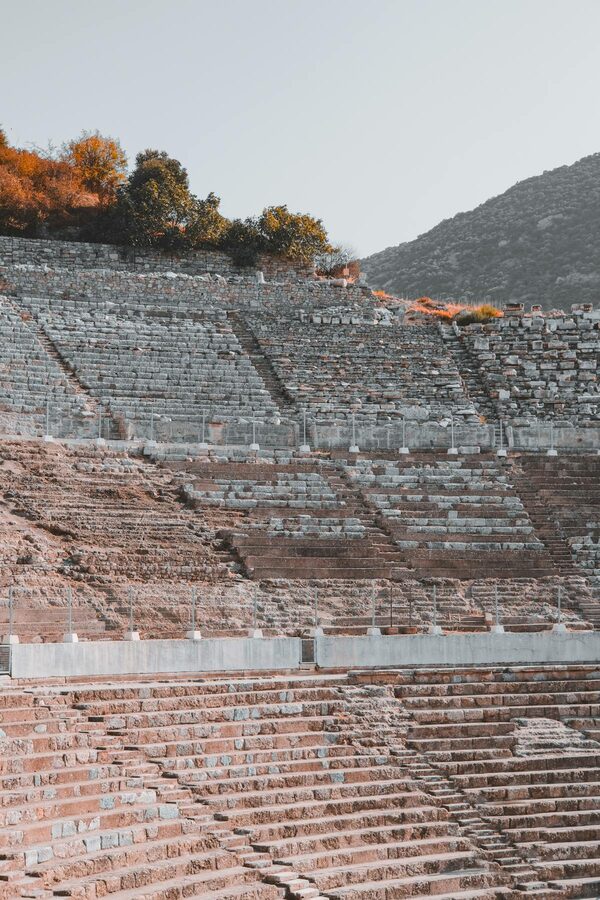 Rows of stone seats in the Ephesus amphitheater with visitors walking the steps