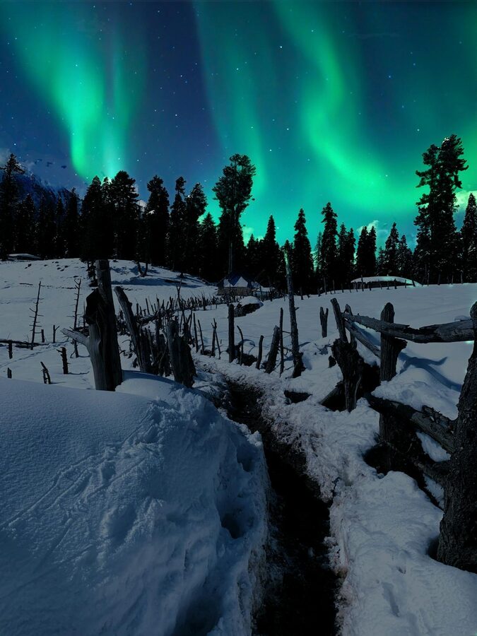 Aurora borealis over a snowy rural area in the Finnish countryside