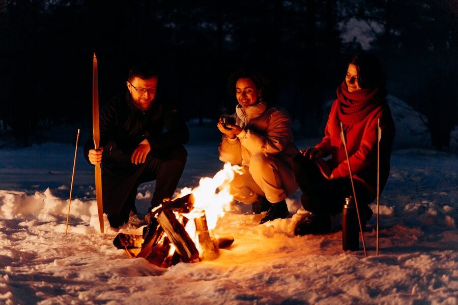 Friends gathered around a campfire in a snowy winter setting