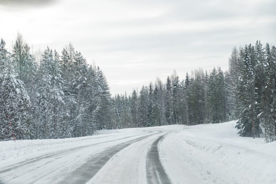 A winter road through snowy forest near Rovaniemi, Finland