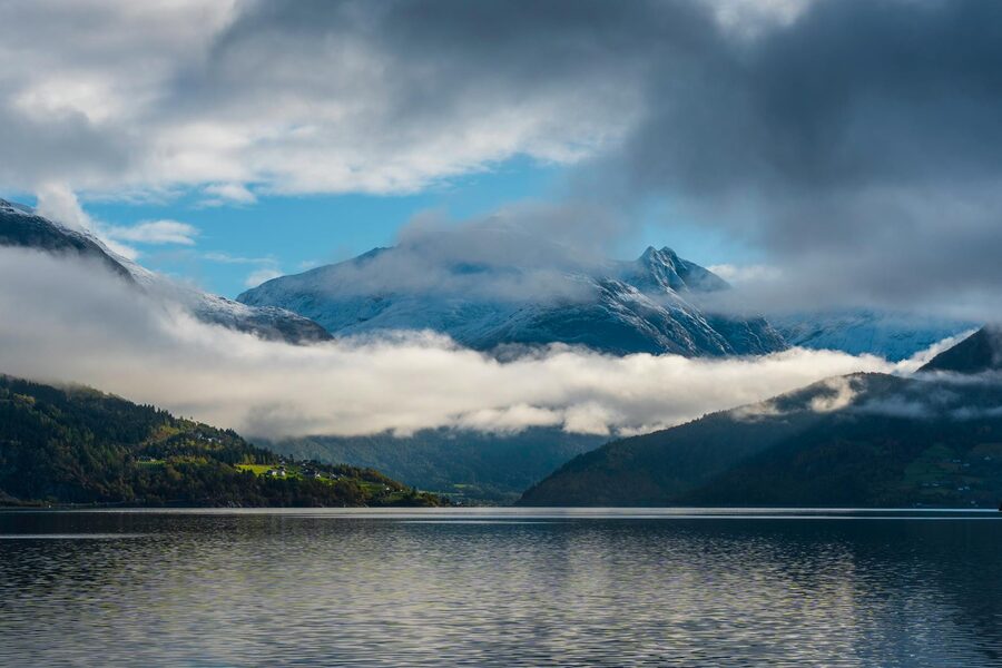 Low clouds hovering over a Norwegian fjord with mountain reflections